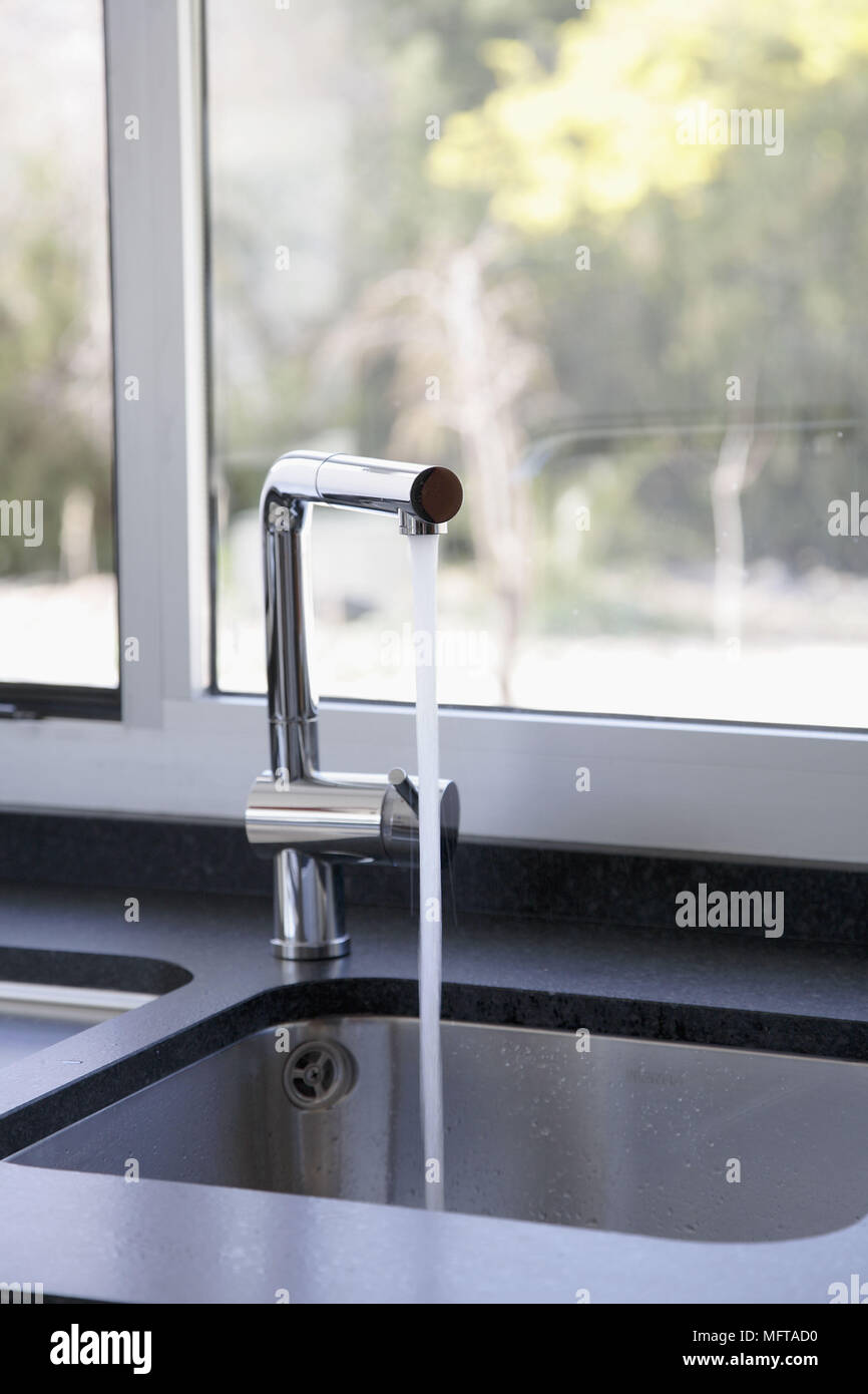Water running from chrome tap fitting on kitchen sink Stock Photo - Alamy
