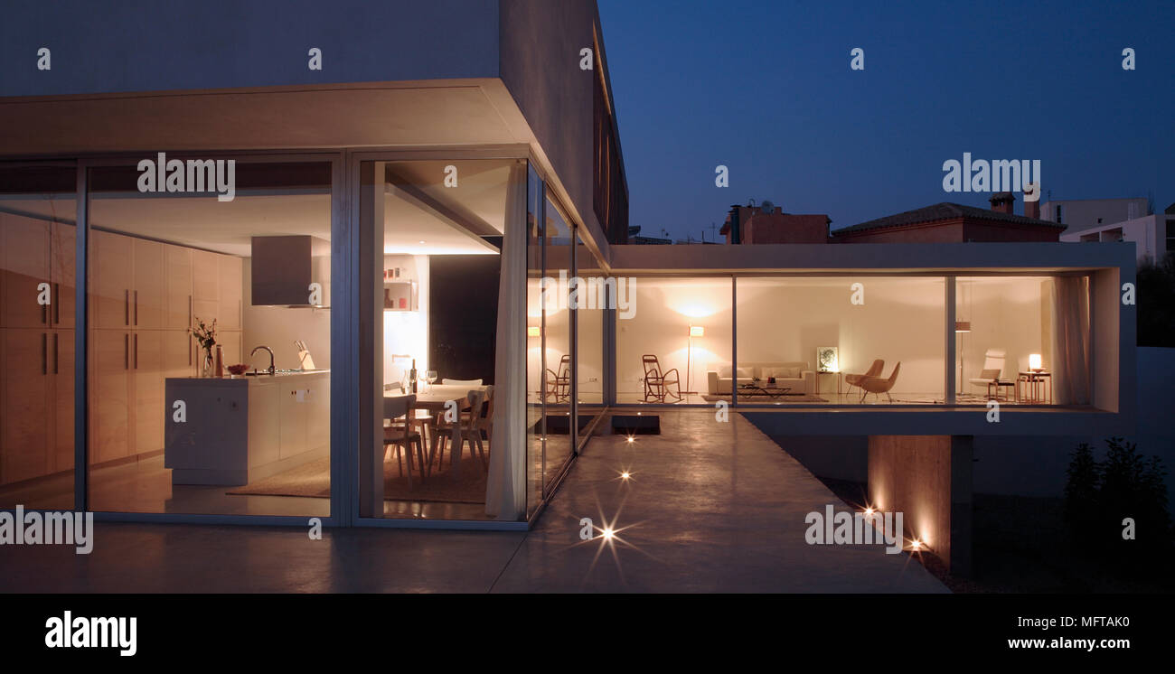 Exterior of modern house lit at night with view through windows to ...