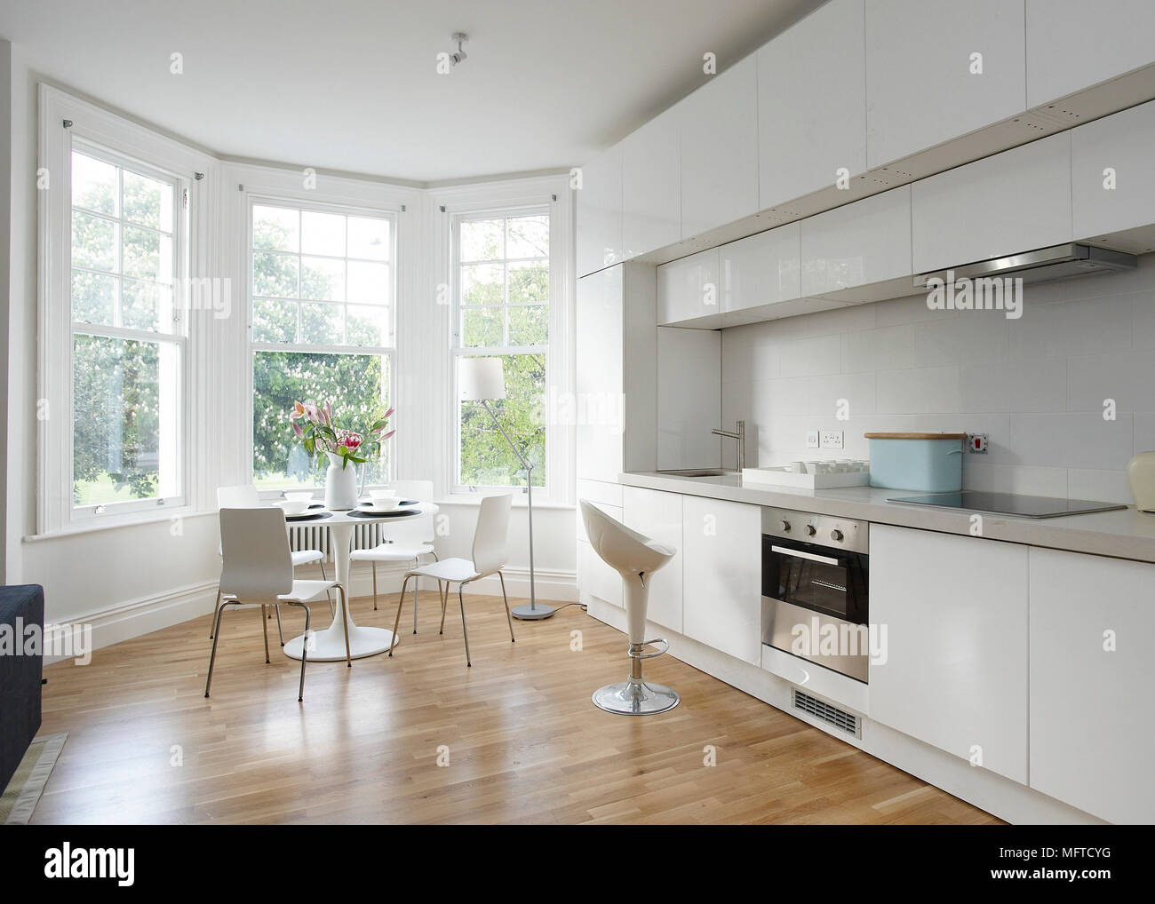 Dining table and chairs in modern kitchen with white fitted units Stock ...