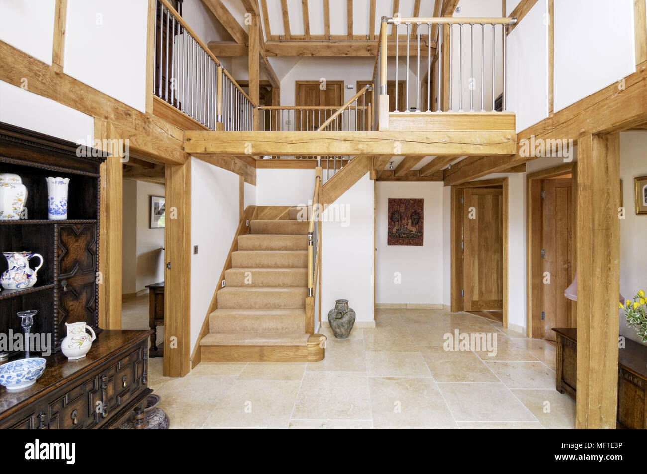 Wooden staircase in double height hallway Stock Photo - Alamy