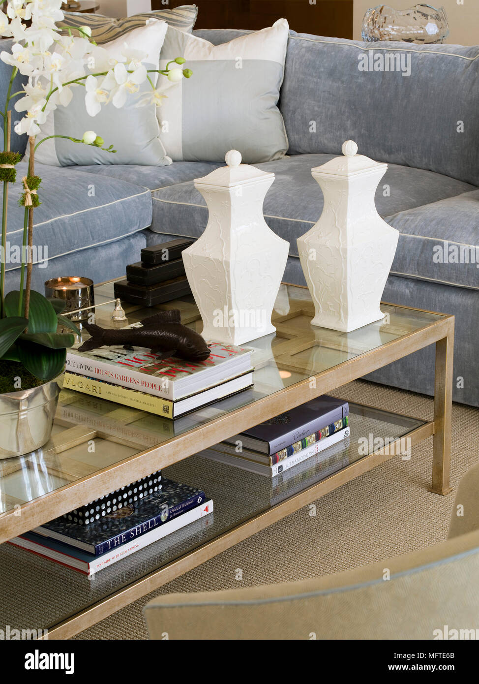 Two pots on glass topped coffee table in front of blue seating Stock ...