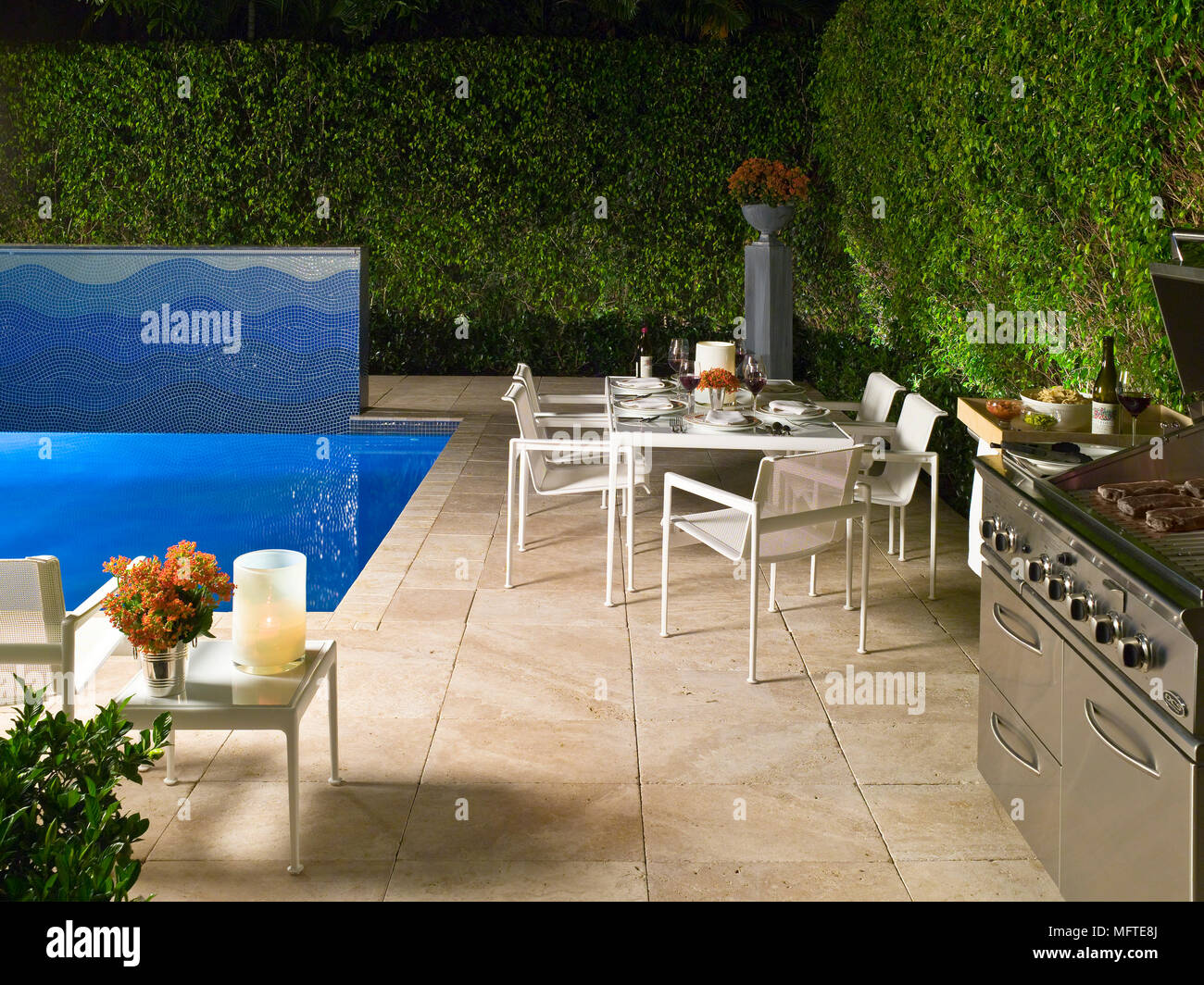 Table and chairs next to swimming pool Stock Photo - Alamy