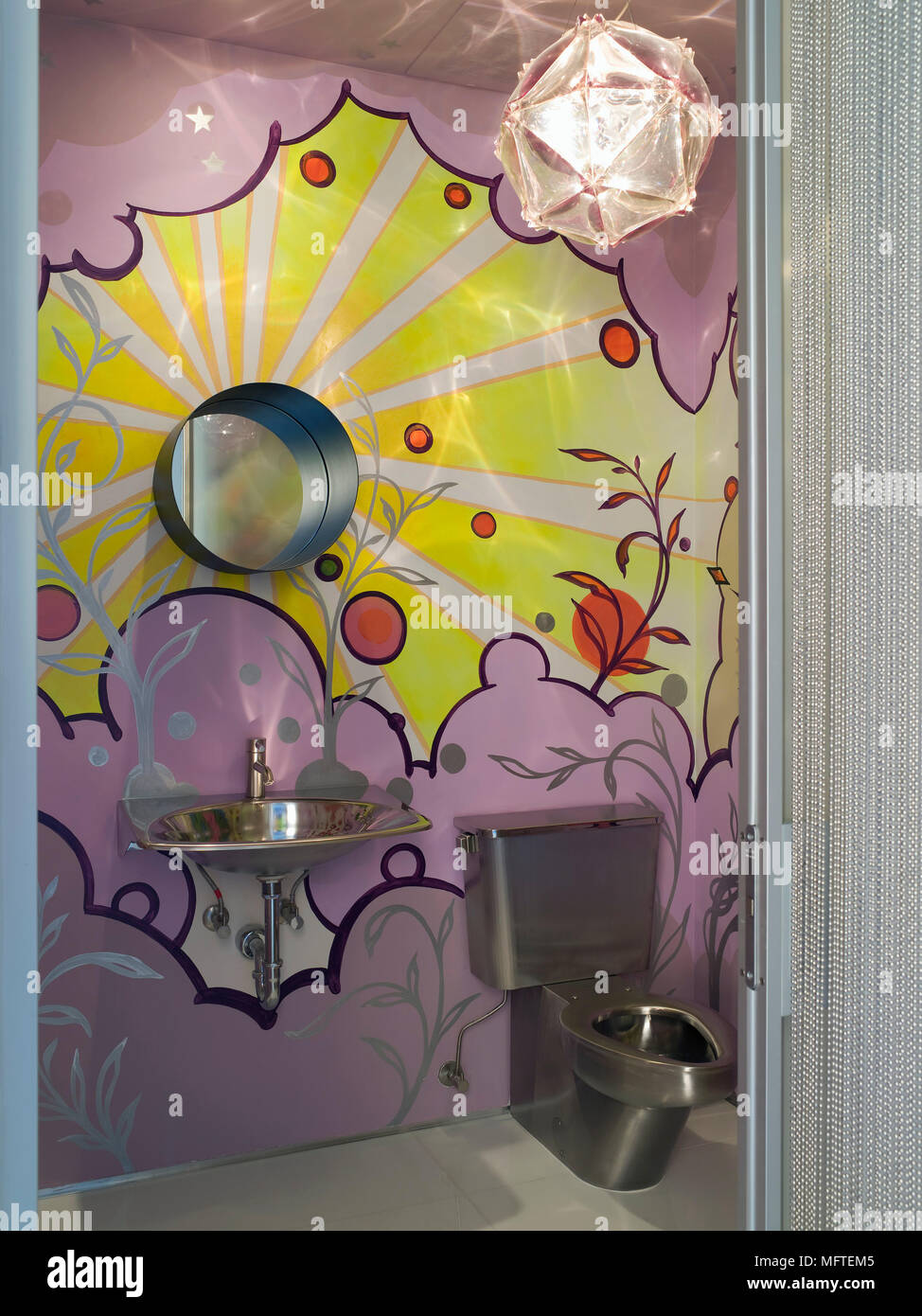 Stainless steel toilet and washbasin in cloakroom with abstract mural ...