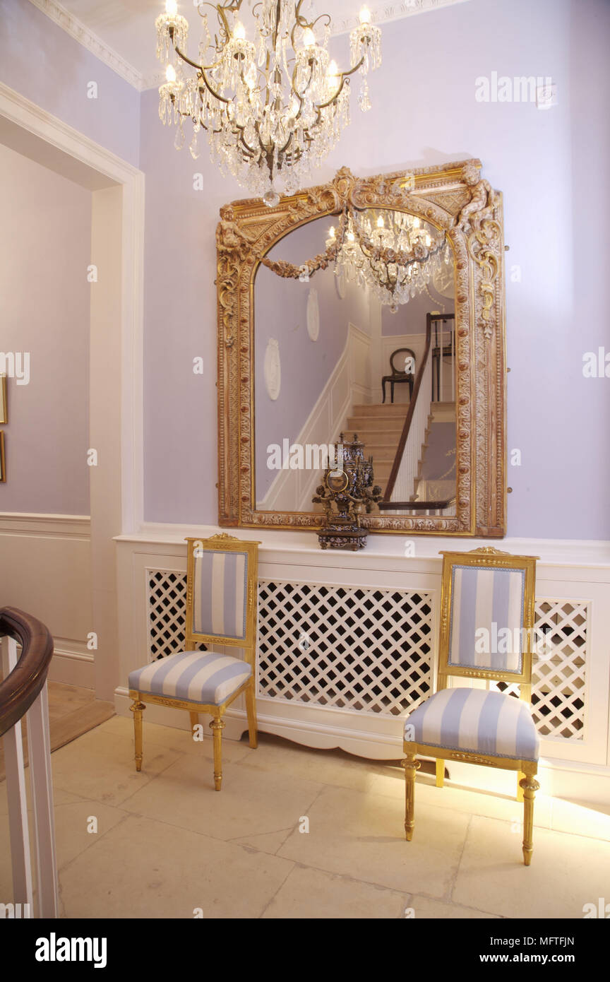 Pair of period chairs below gilt mirror Stock Photo - Alamy