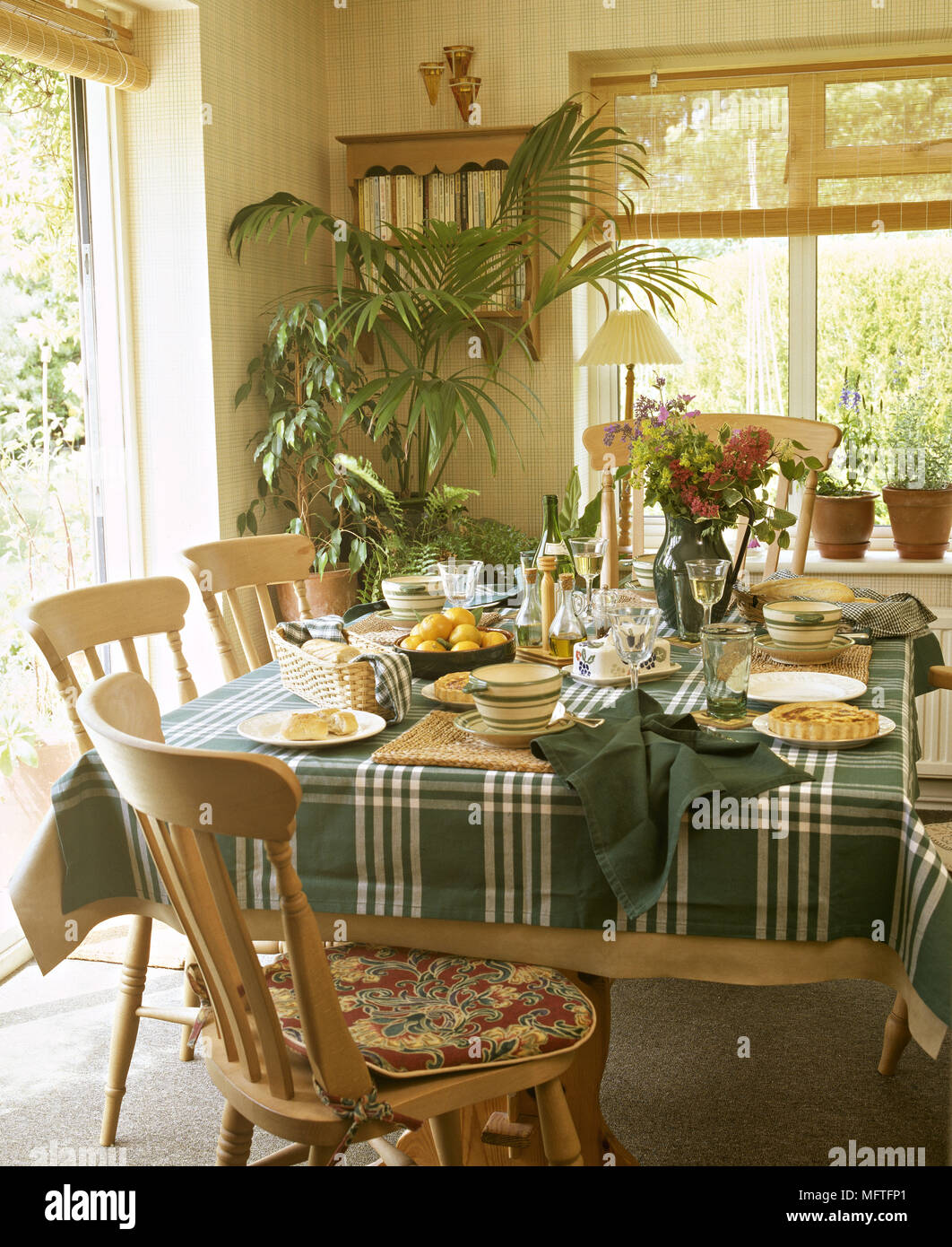 Sunny country dining room with pine table and chairs set for lunch ...