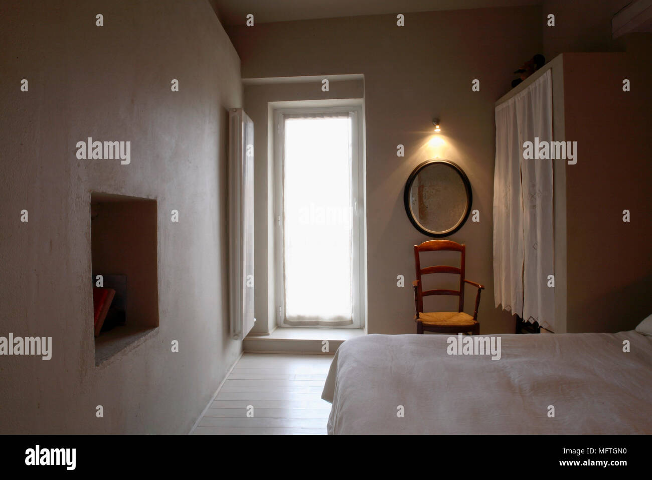 Dimly lit bedroom with oval mirror and glass door Stock Photo - Alamy