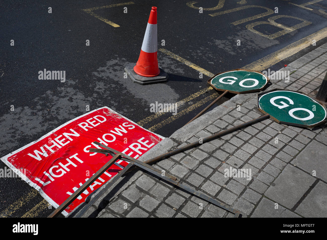 Two GO and Wait traffic road signs lie by the kerb on the ground in ...
