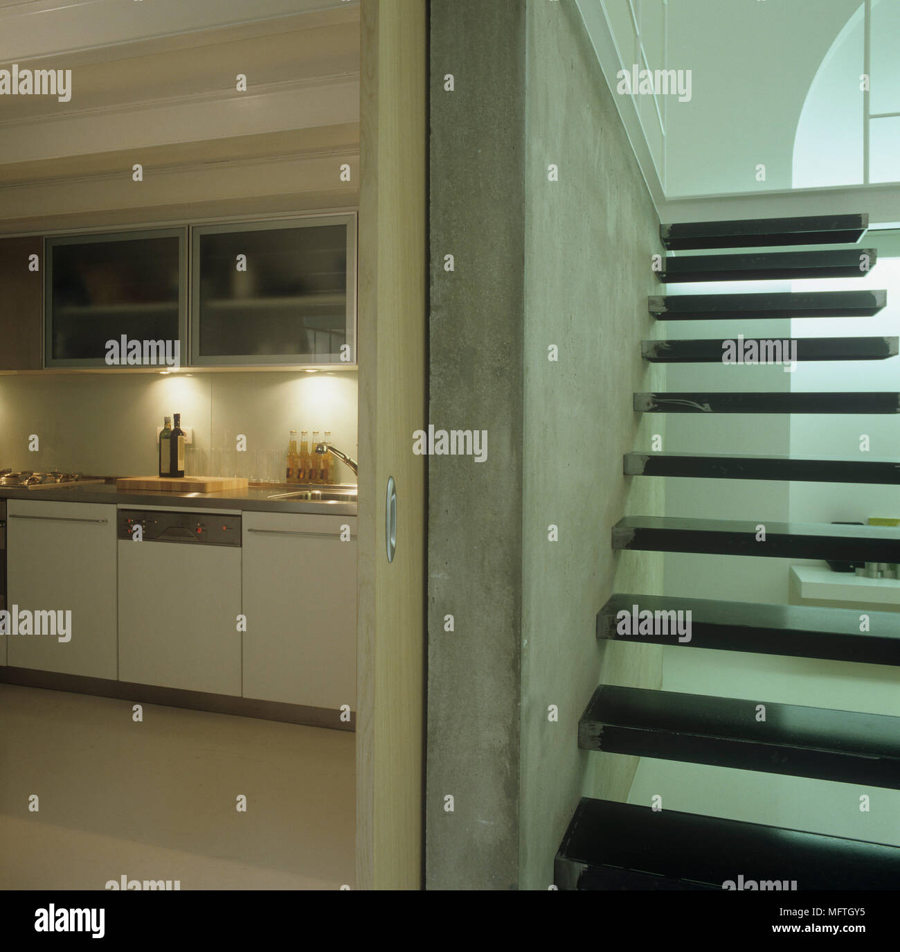Staircase next to modern kitchen with sliding door Stock Photo - Alamy