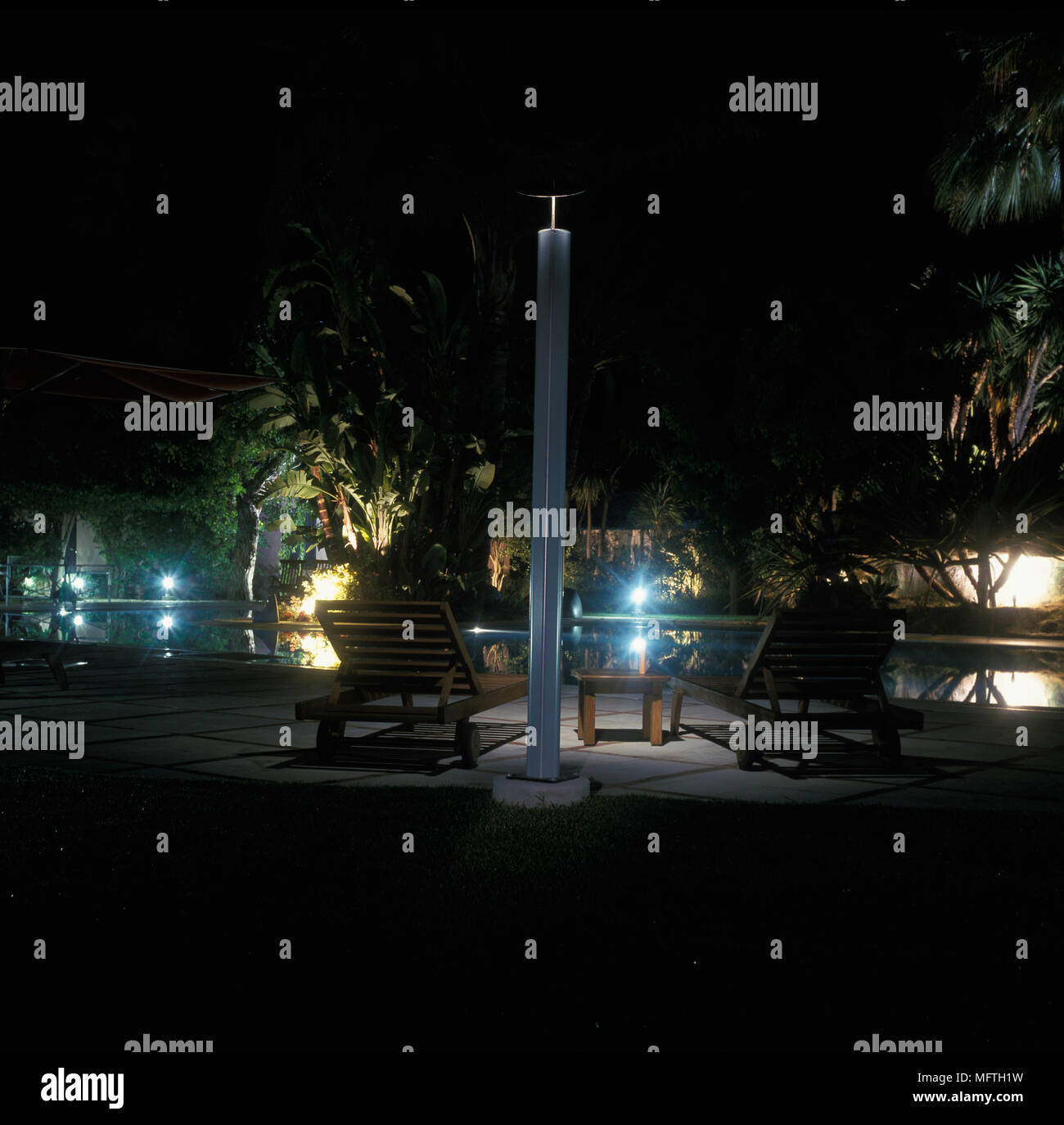 Outside pool at night with sun loungers Stock Photo - Alamy