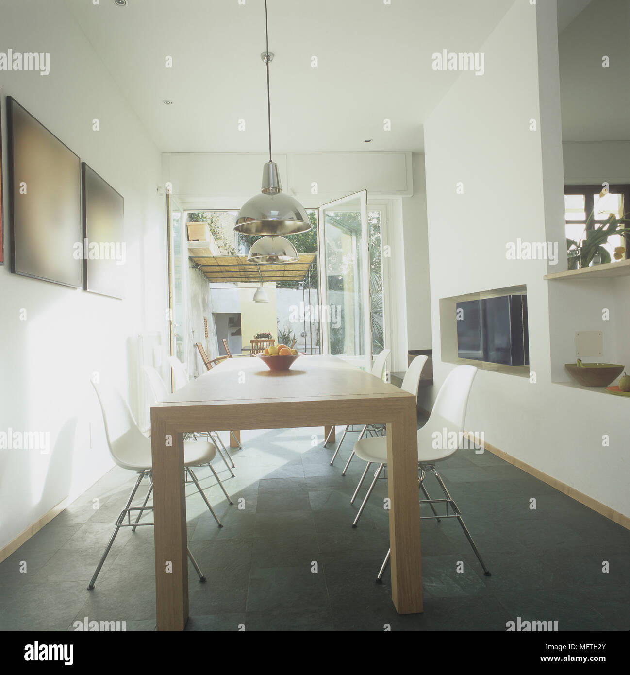 Wooden table with metal ceiling lights suspended above Stock Photo - Alamy