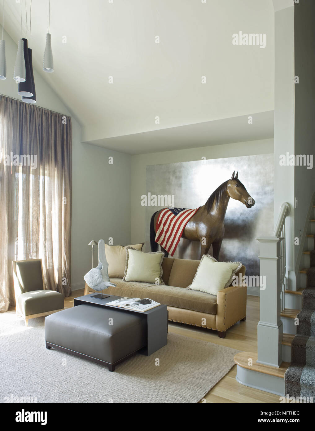 Upholstered ottoman in front of sofa in modern open plan sitting room ...