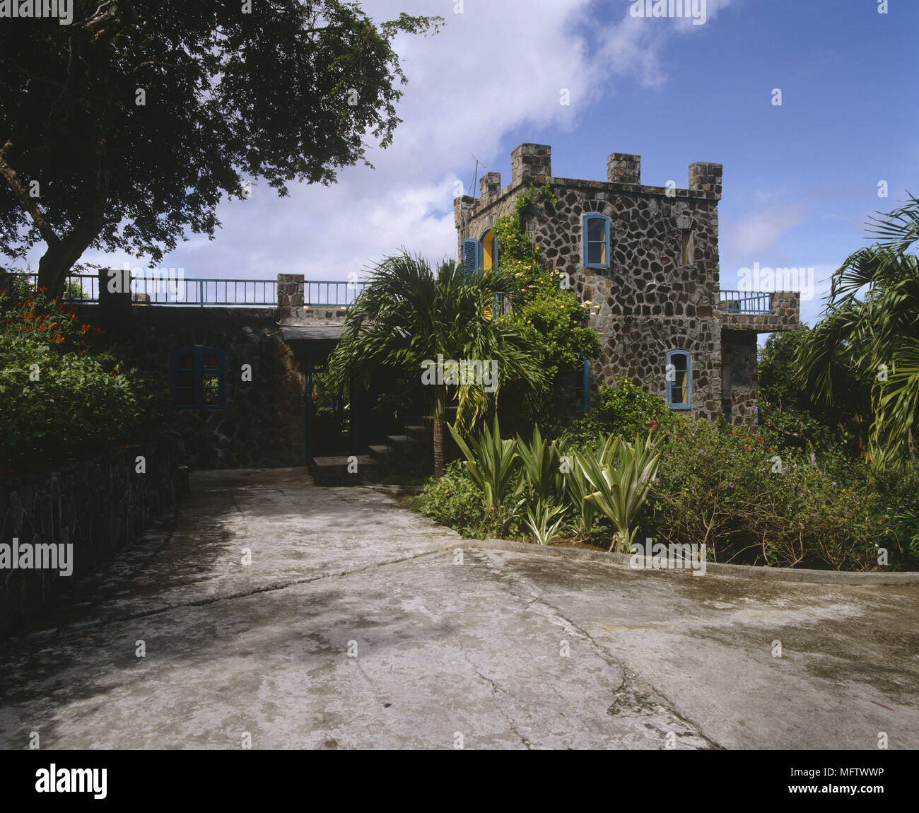 Exterior of castellated stone building with concrete drive and tropical ...
