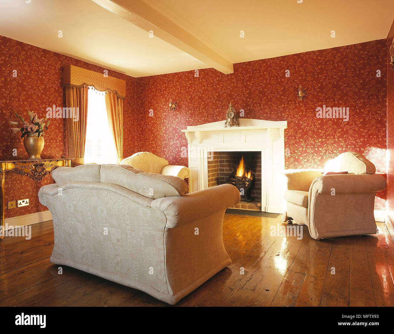 Sofa and armchair in front of fireplace with open fire Stock Photo - Alamy
