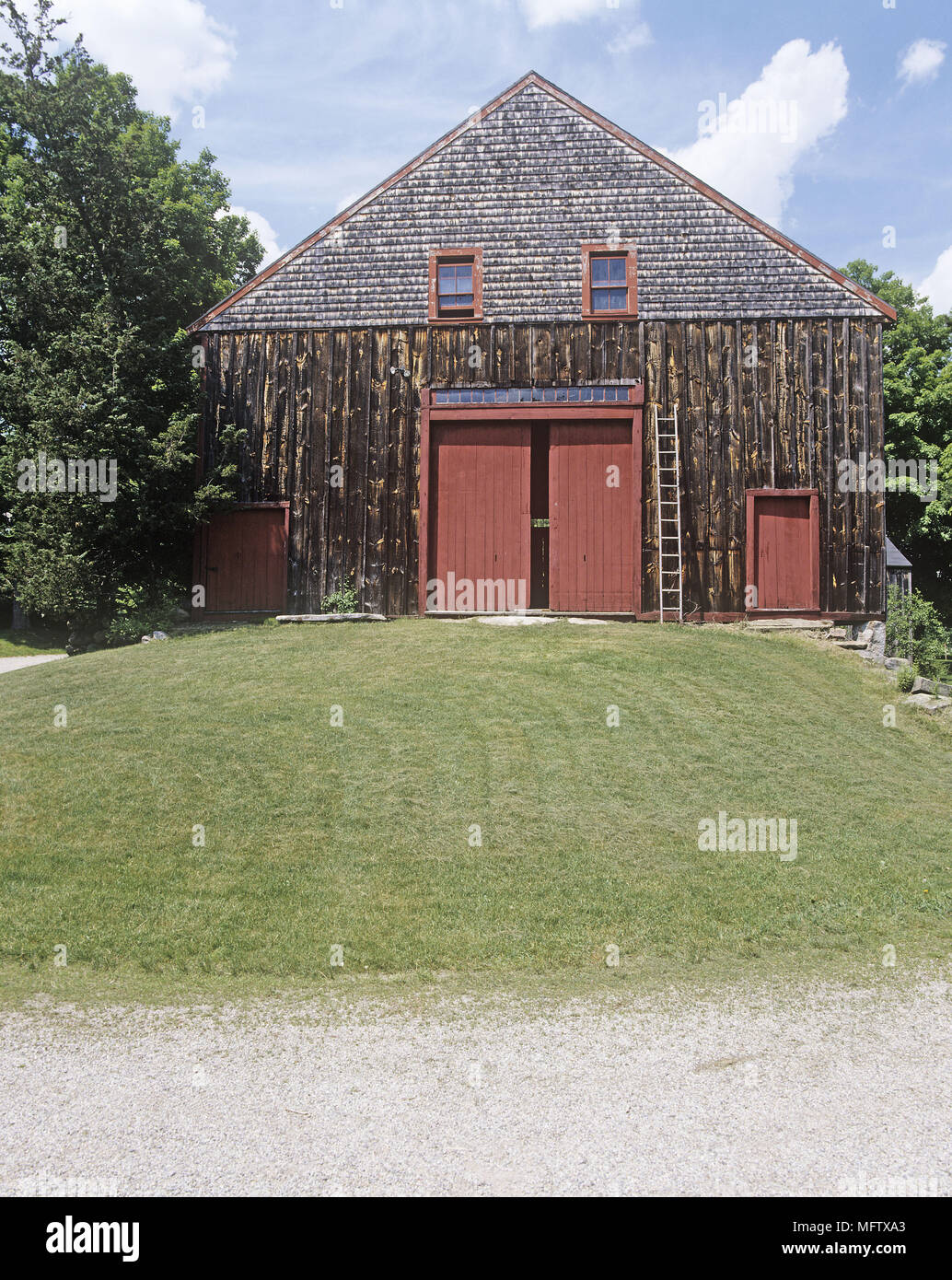 The exterior of a traditional barn with dark wood panelling red doors ...