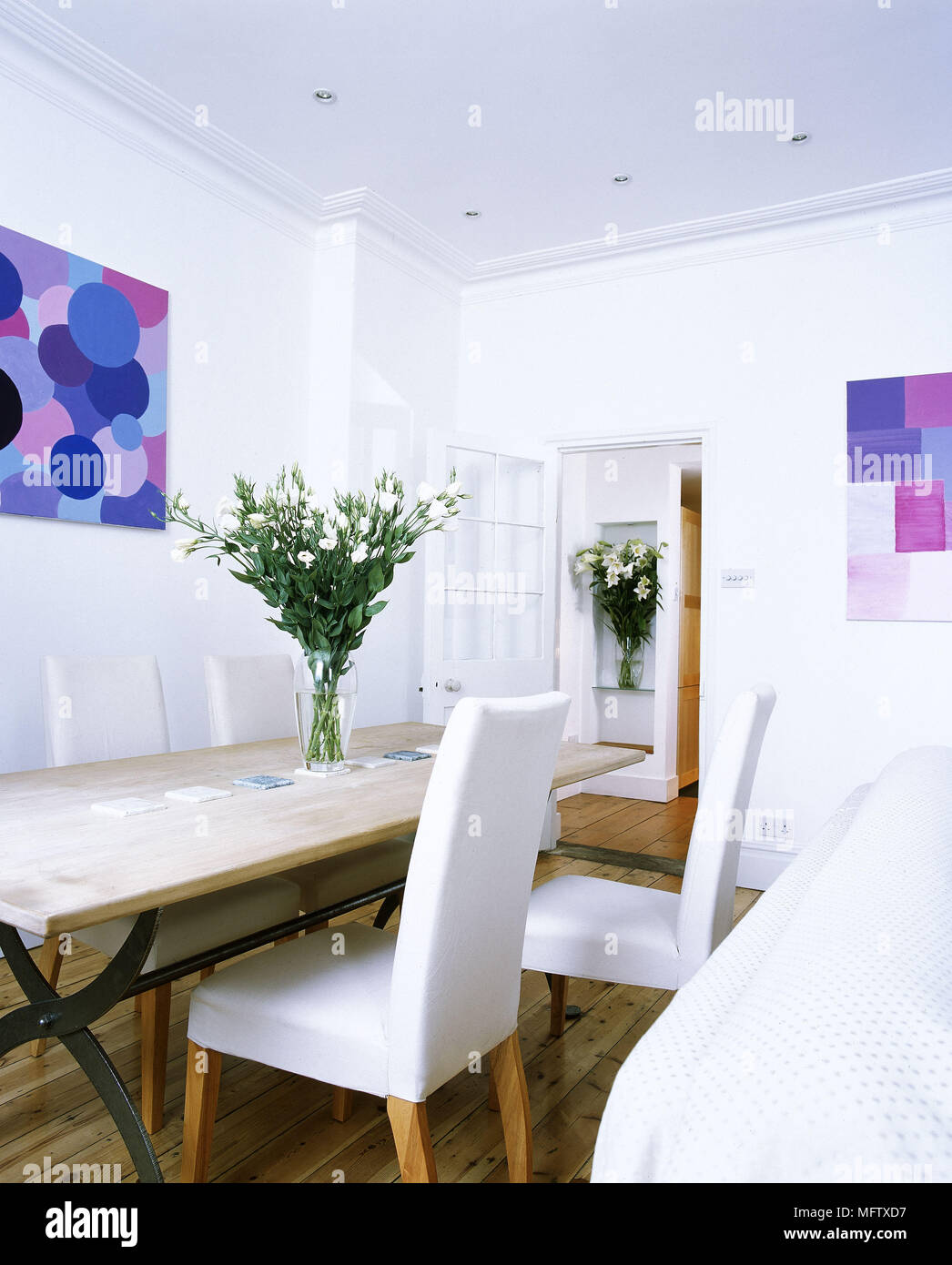 White sitting room with dining area with table and upholstered chairs ...