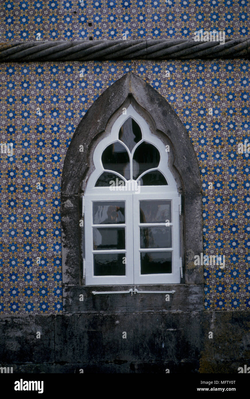 A detail of the exterior of a decorative, arched window set in a tiled ...