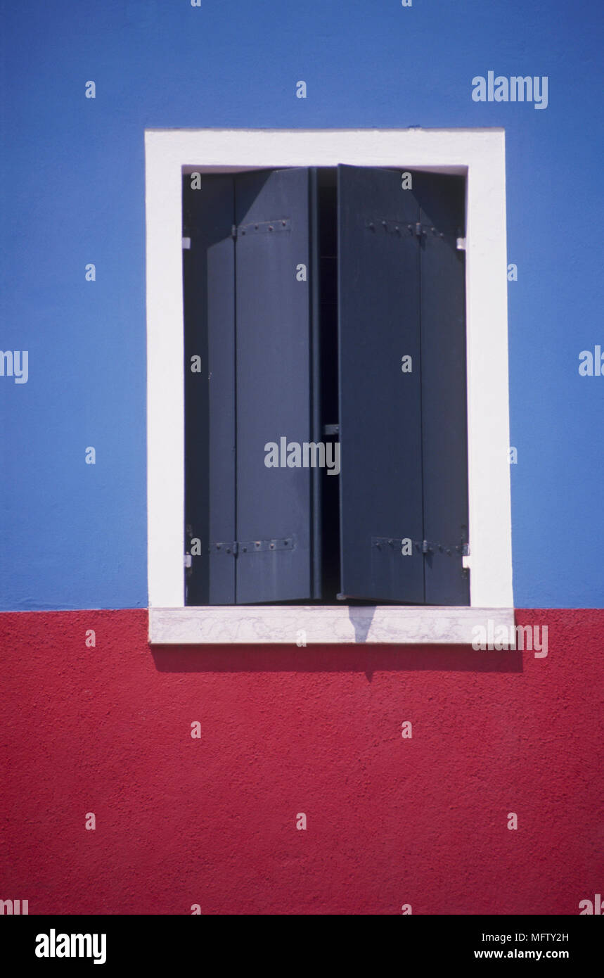 A detail of the exterior of a simple painted window with shutters ...