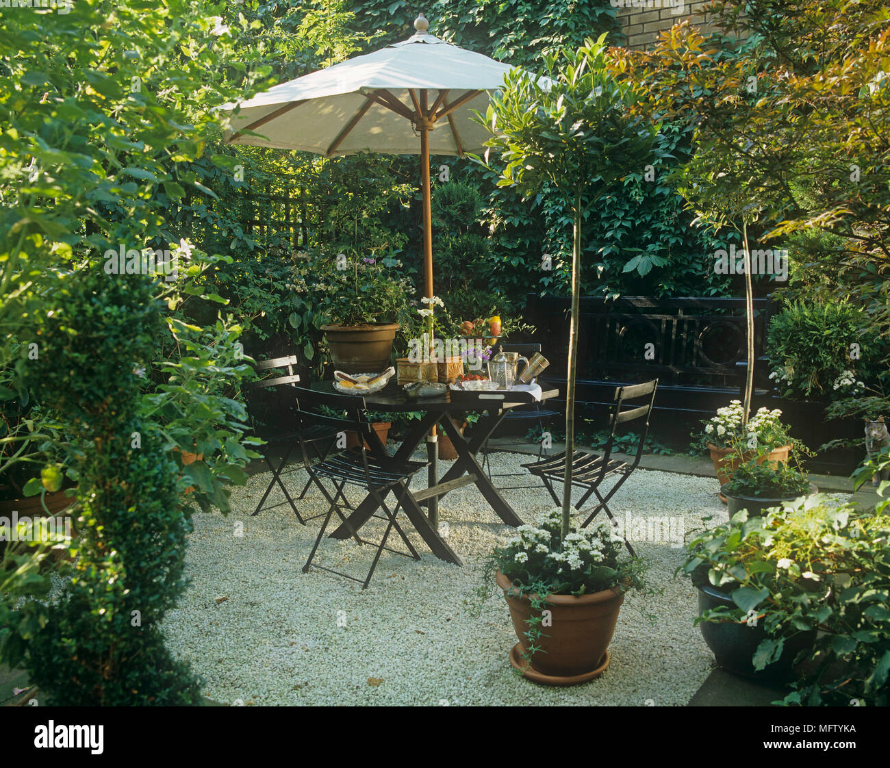 Table and chairs with parasol in town garden patio area Stock Photo - Alamy