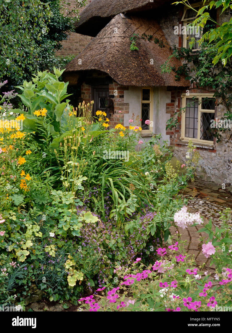 Exterior of stone country cottage with thatched roof and cottage garden ...