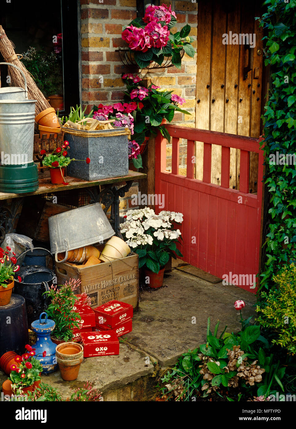Pots and buckets on and under table next to red gate Stock Photo - Alamy