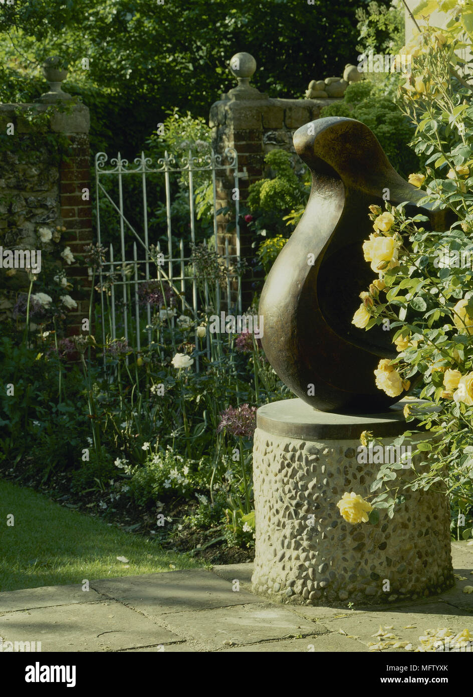 Garden gate and wall flowers beds yellow roses sculpture on plinth ...