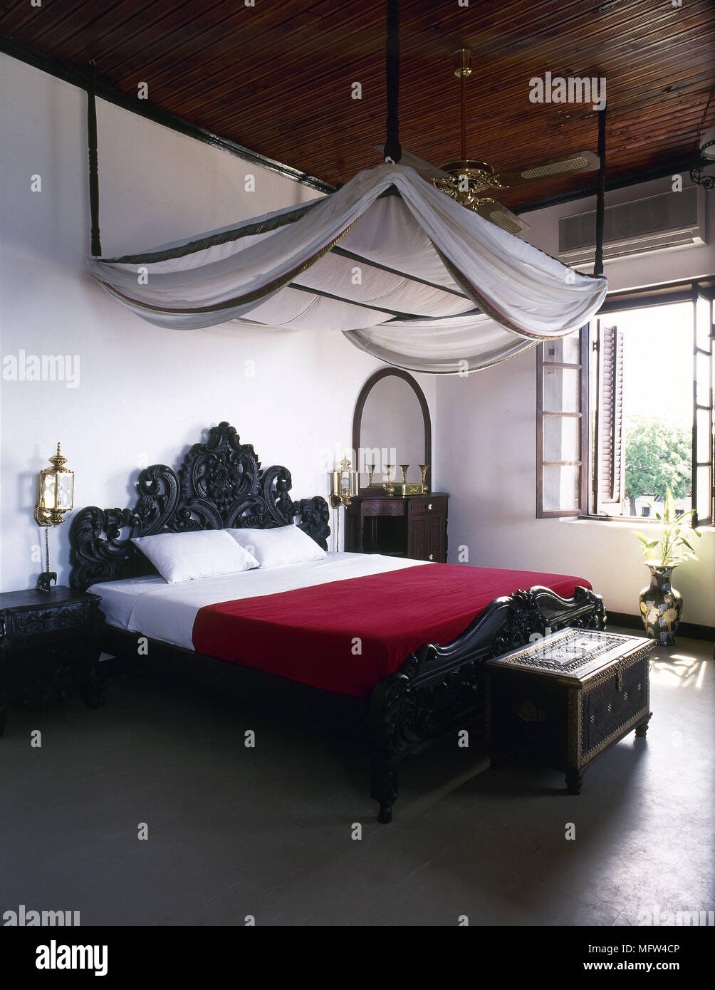 Arabic style bedroom with carved wooden bed and mosquito net on canopy ...