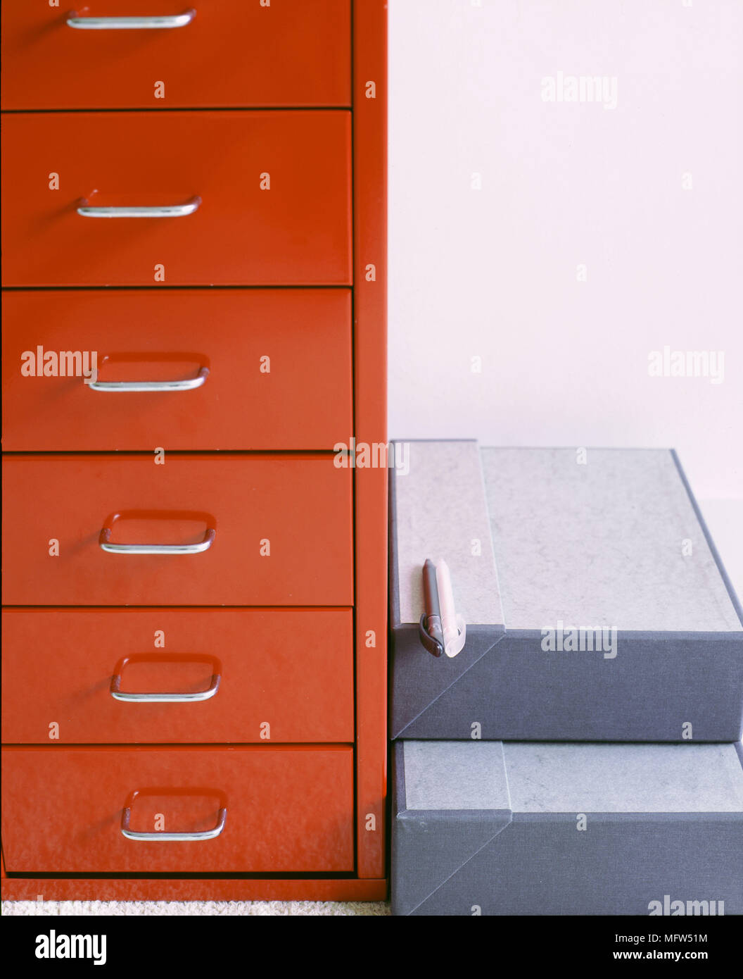 Modern red six drawer filing cabinet next to stacked grey magazine ...