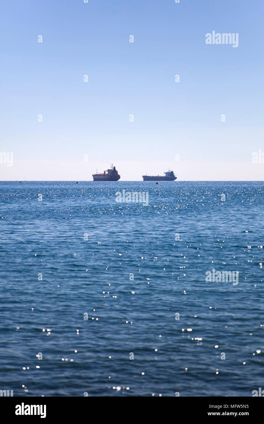 Cargo ships on the horizon of blue sea Stock Photo - Alamy