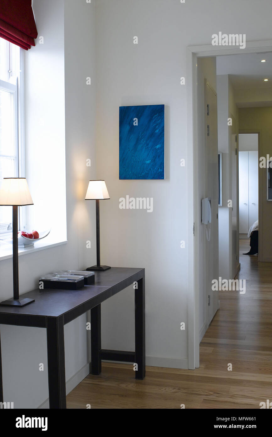 Matching lamps on a side table under a window in a modern hallway Stock ...