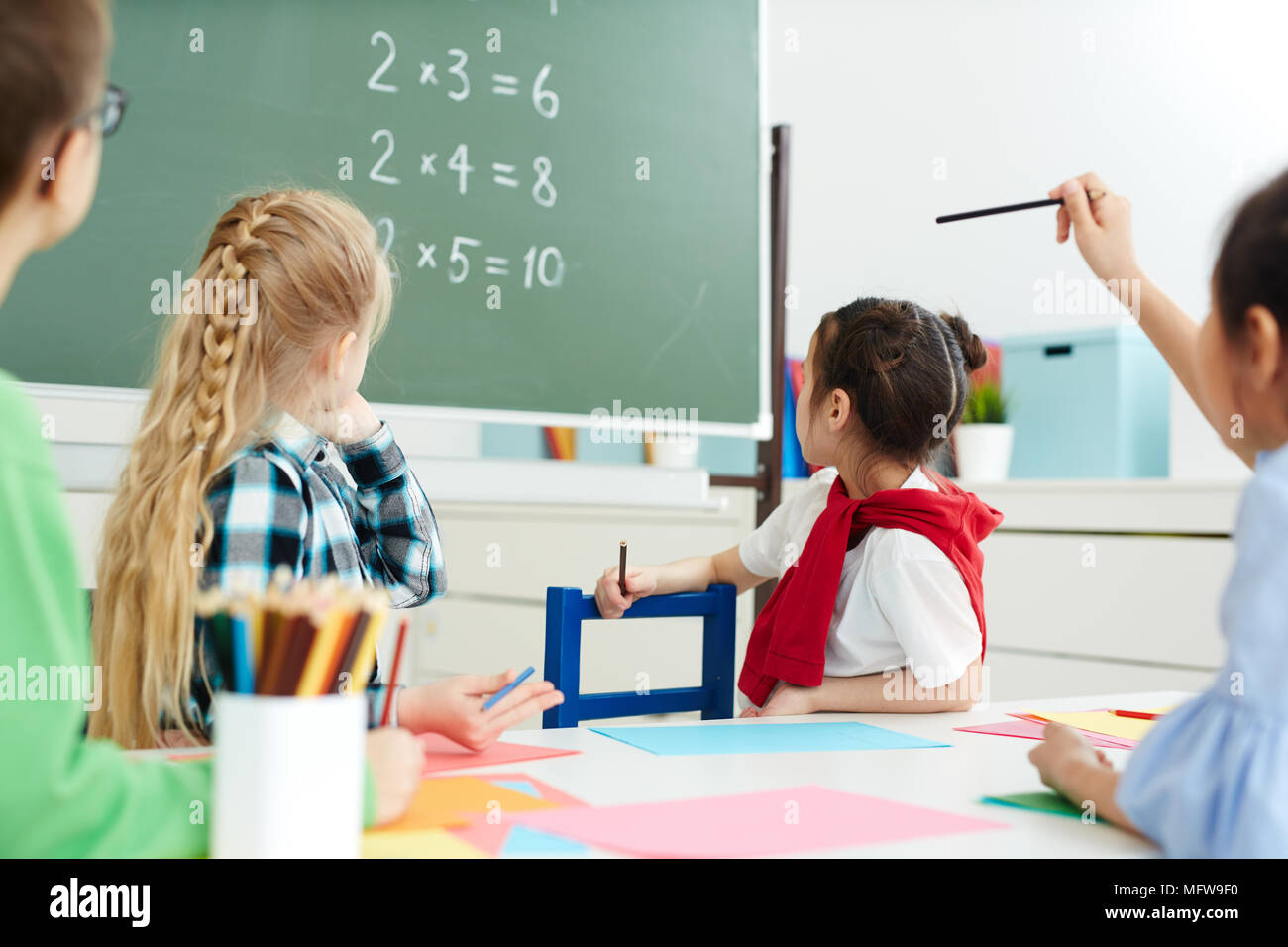 Elementary school kids sitting in classroom and looking at blackboard ...