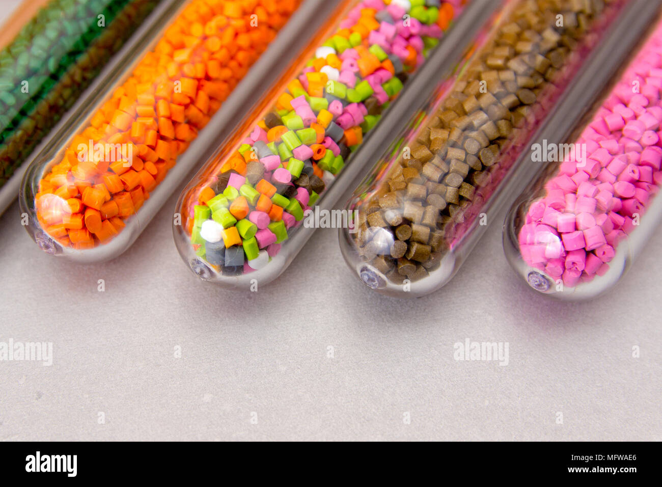 Plastic pellets .Polymeric dye in test tubes on gray background ...