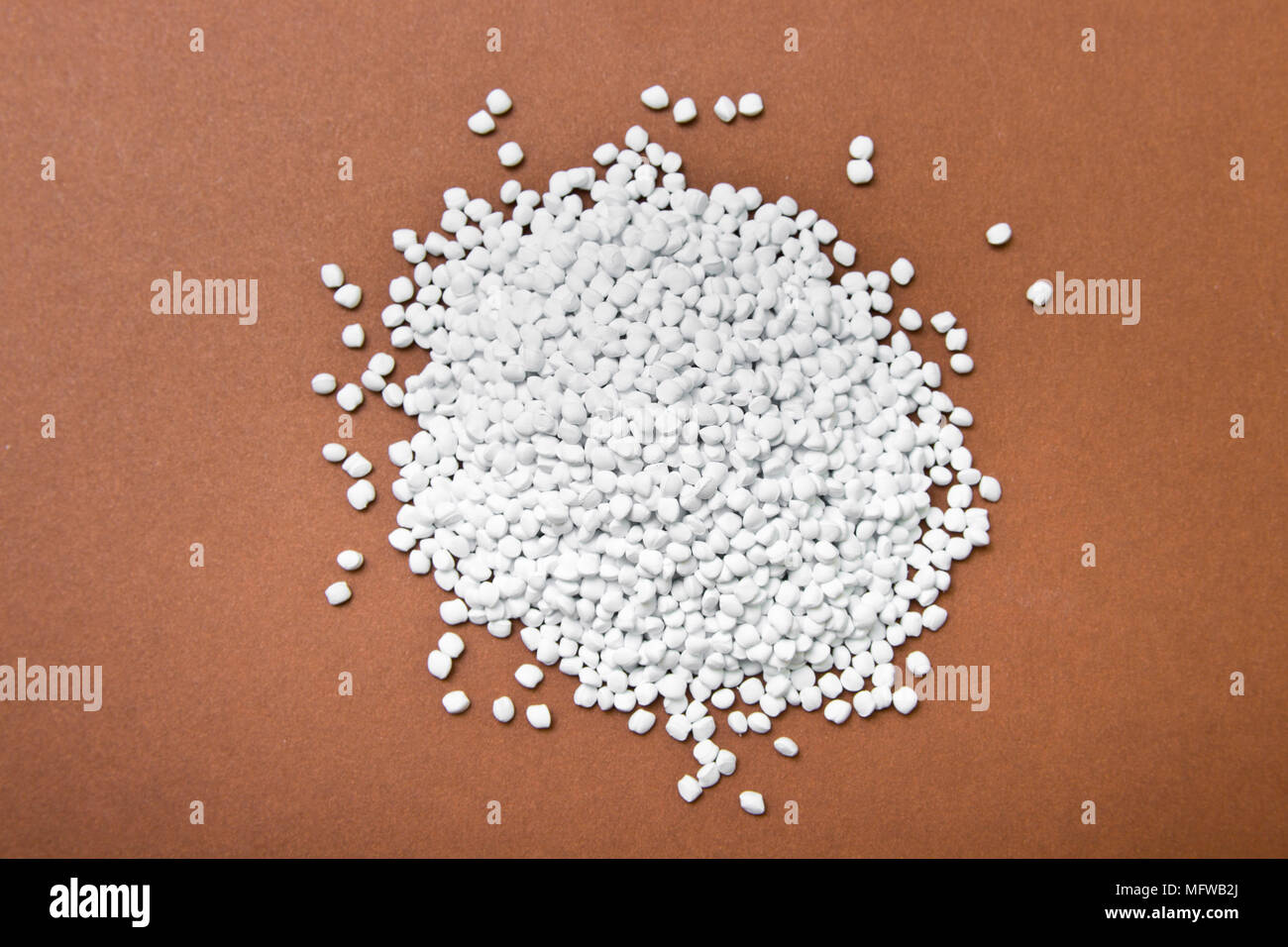 Plastic pellets. White Colorant for plastics on a brown background ...