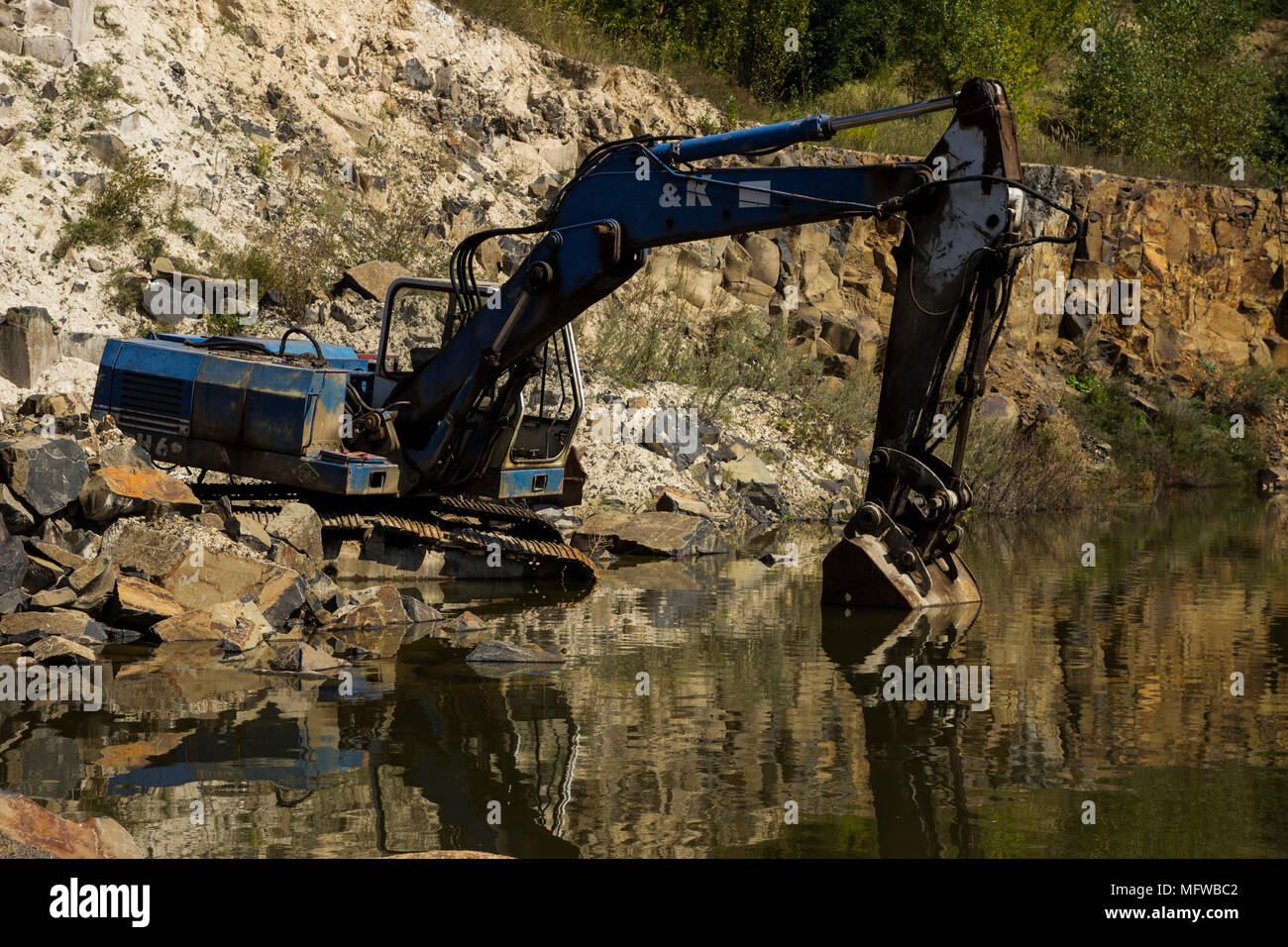 Broken excavator and basalt columns rocks. Heavy industry. Stone ...