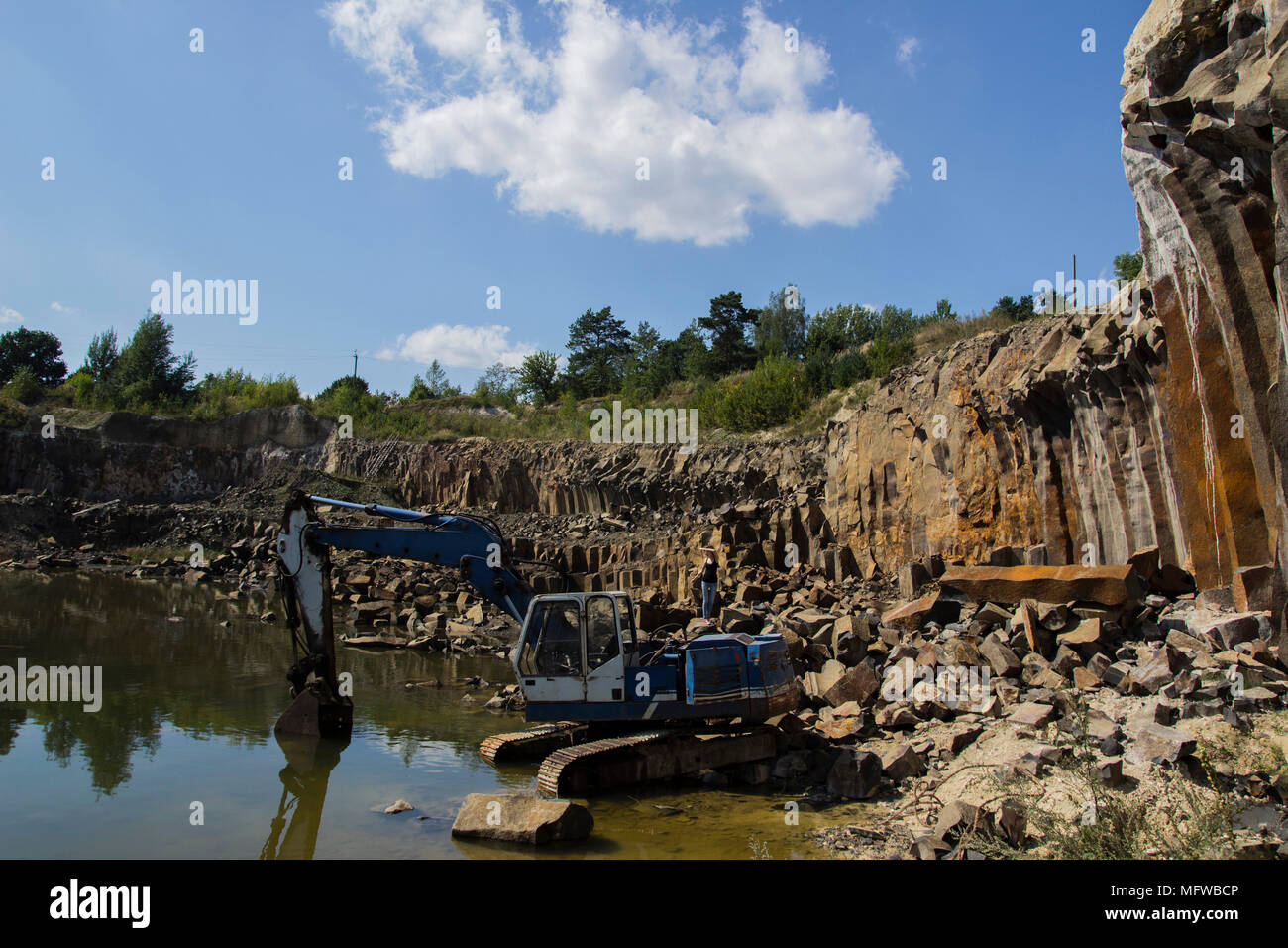 Broken excavator and basalt columns rocks. Heavy industry. Stone ...