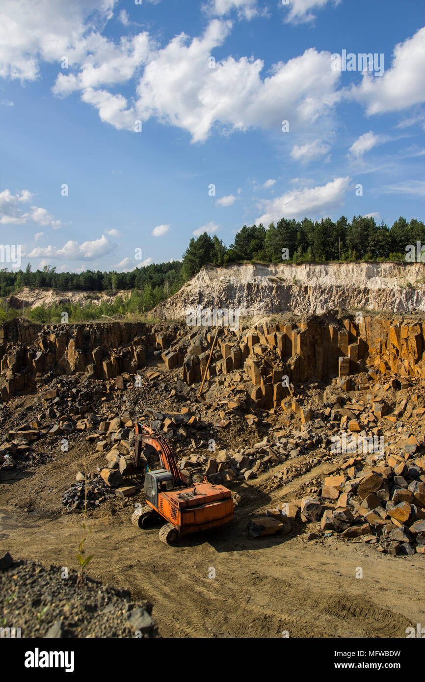 Excavator and basalt columns rocks. Heavy industry. Stone excavation ...