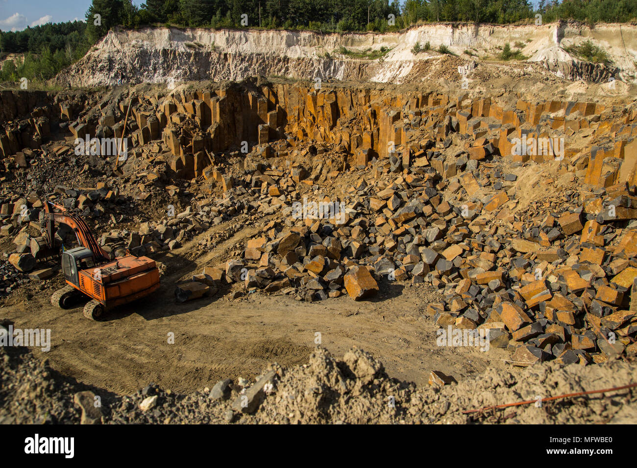 Excavator and basalt columns rocks. Heavy industry. Stone excavation ...
