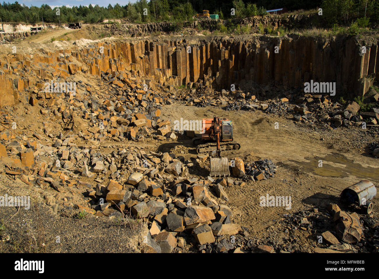 Excavator and basalt columns rocks. Heavy industry. Stone excavation ...