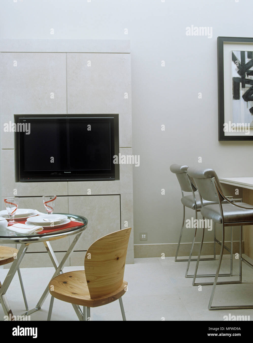 Large built in television facing circular table with wooden chairs next ...