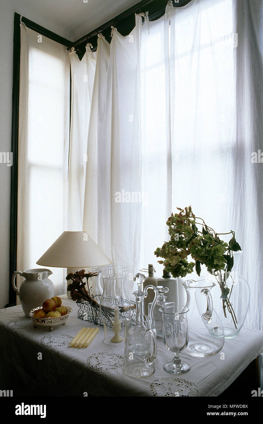 A detail of a table beneath a window, sheer curtain, table, collection ...