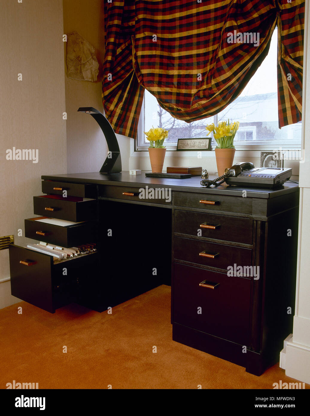 Home office with black wood desk set in recess below window Stock Photo ...