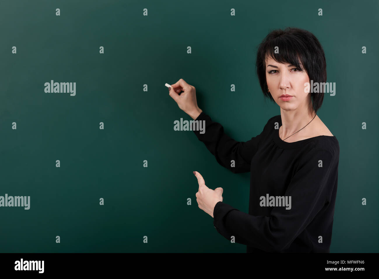 strict teacher posing by chalk Board, learning concept, green ...