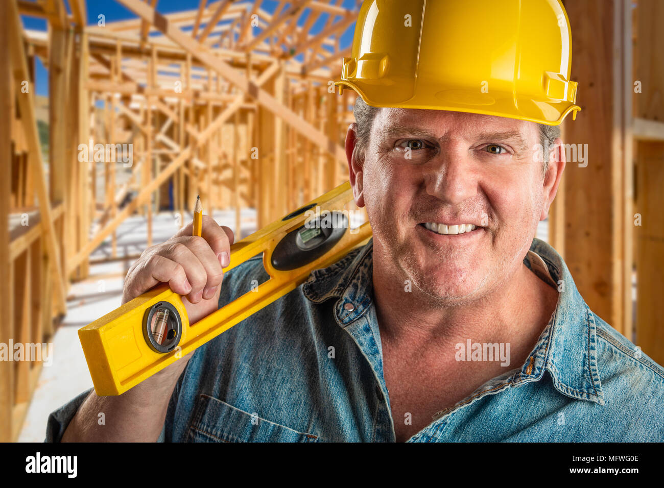 Smiling Contractor in Hard Hat Holding Level and Pencil At Construction ...
