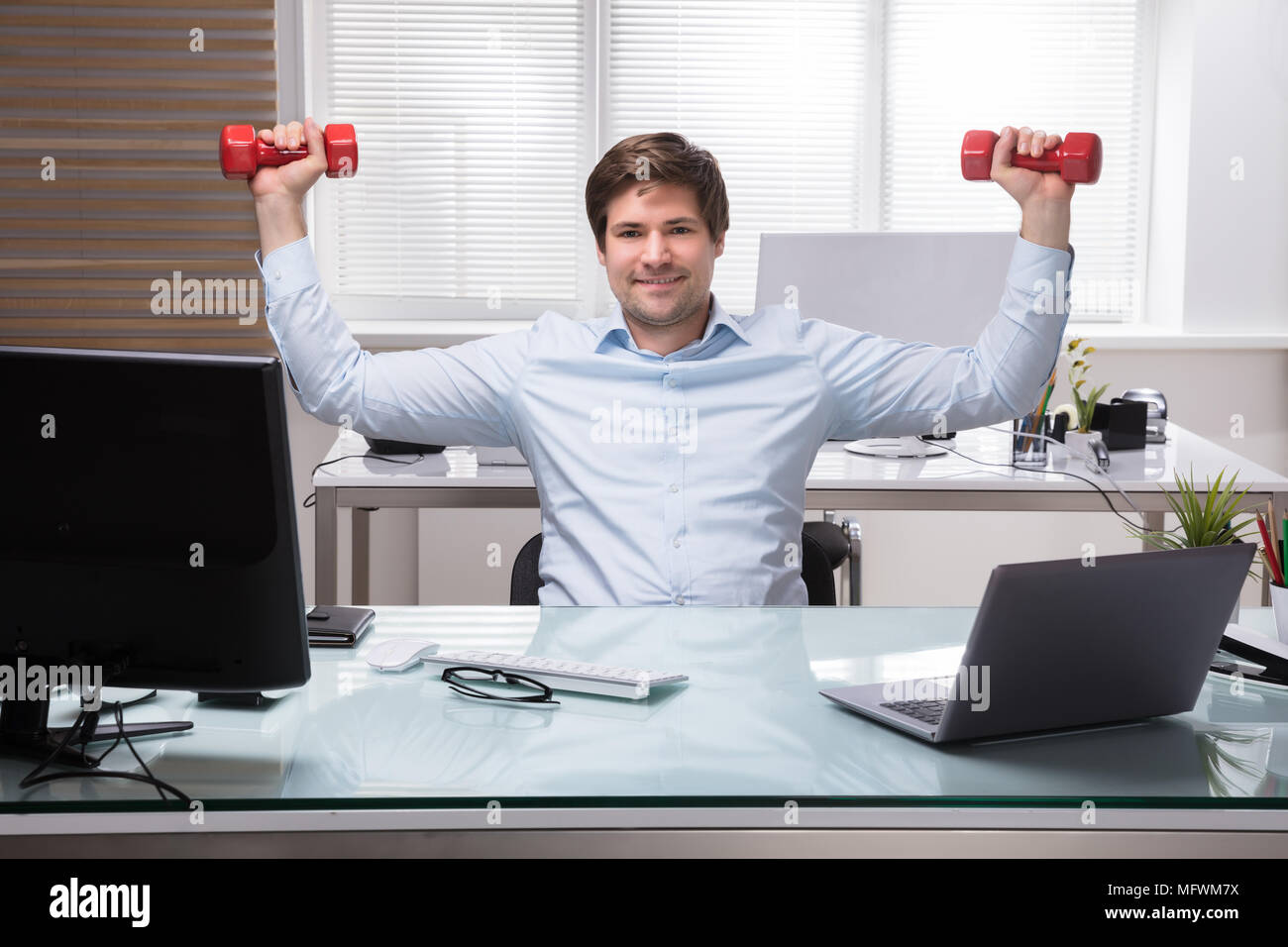 Happy Young Businessman Doing Exercise With Red Dumbbell Stock Photo ...
