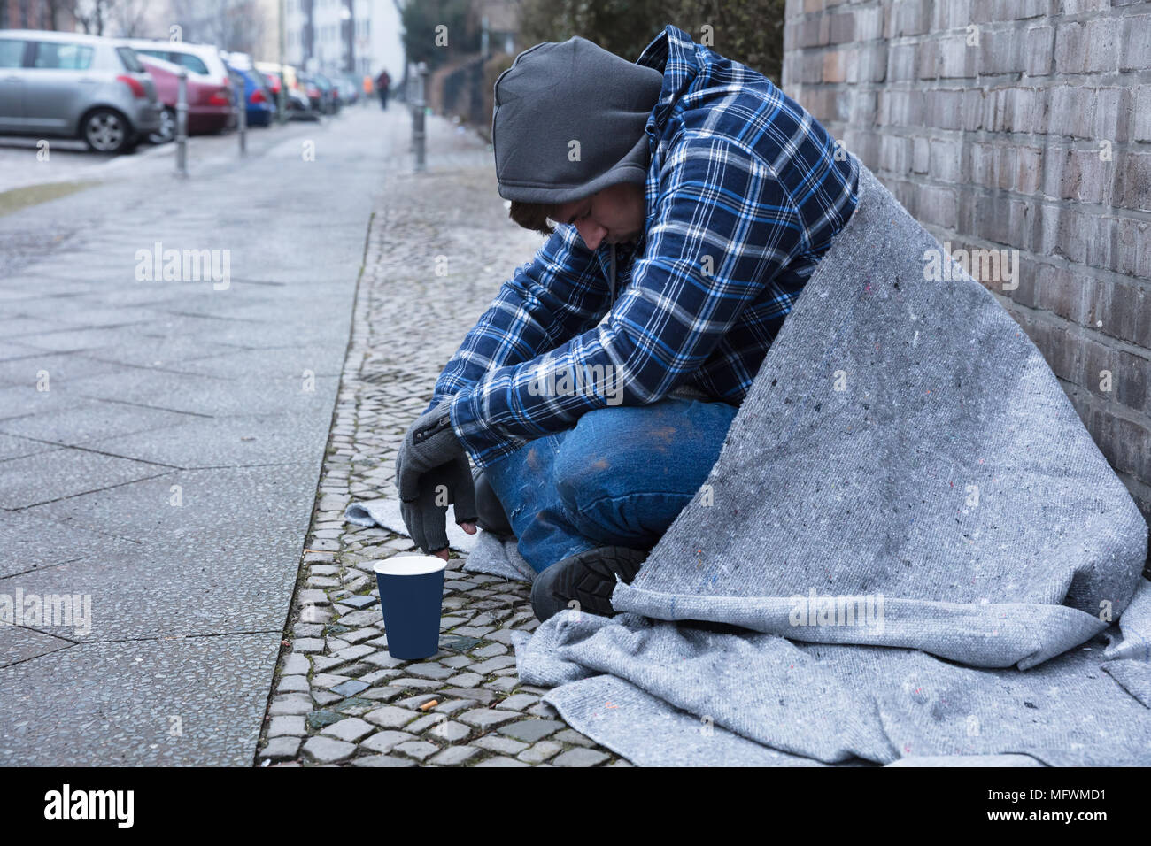 Side View Of A Male Beggar Sitting On Street Near Disposable Cup Stock ...