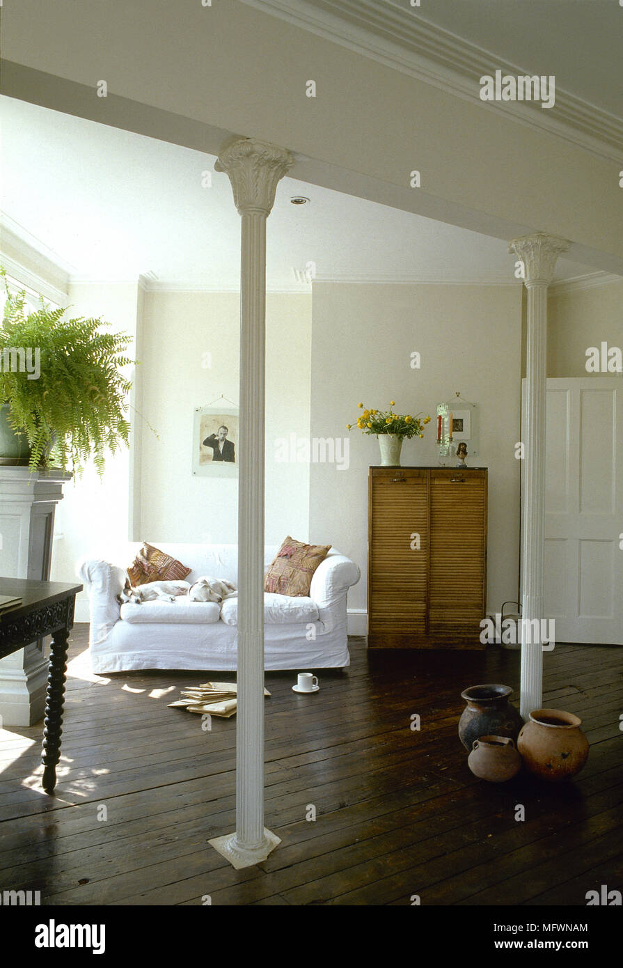Modern, open sitting room with wood floor, pillars, side cabinet, and ...