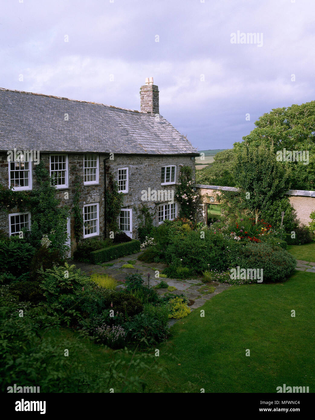 Exterior view of a rustic stone cottage with a lush, green lawn and ...