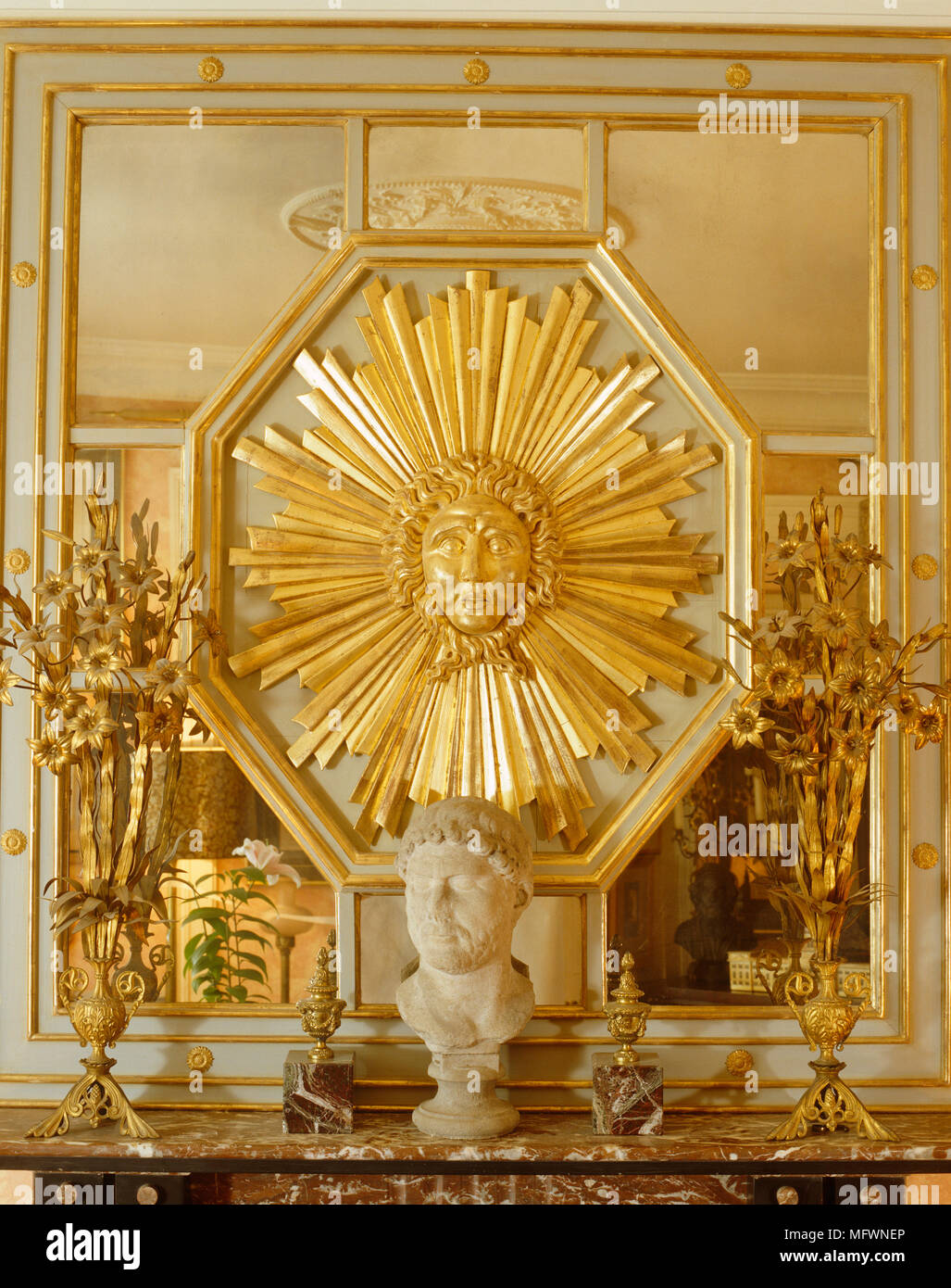Gold mirrored panel with sunray face sculpture above marble mantelpiece ...