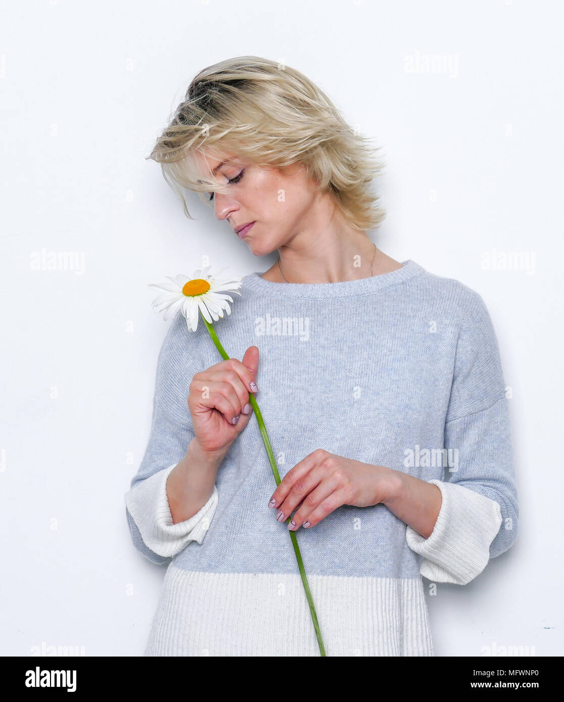 Pretty woman holds chamomile flower in her hands Stock Photo - Alamy
