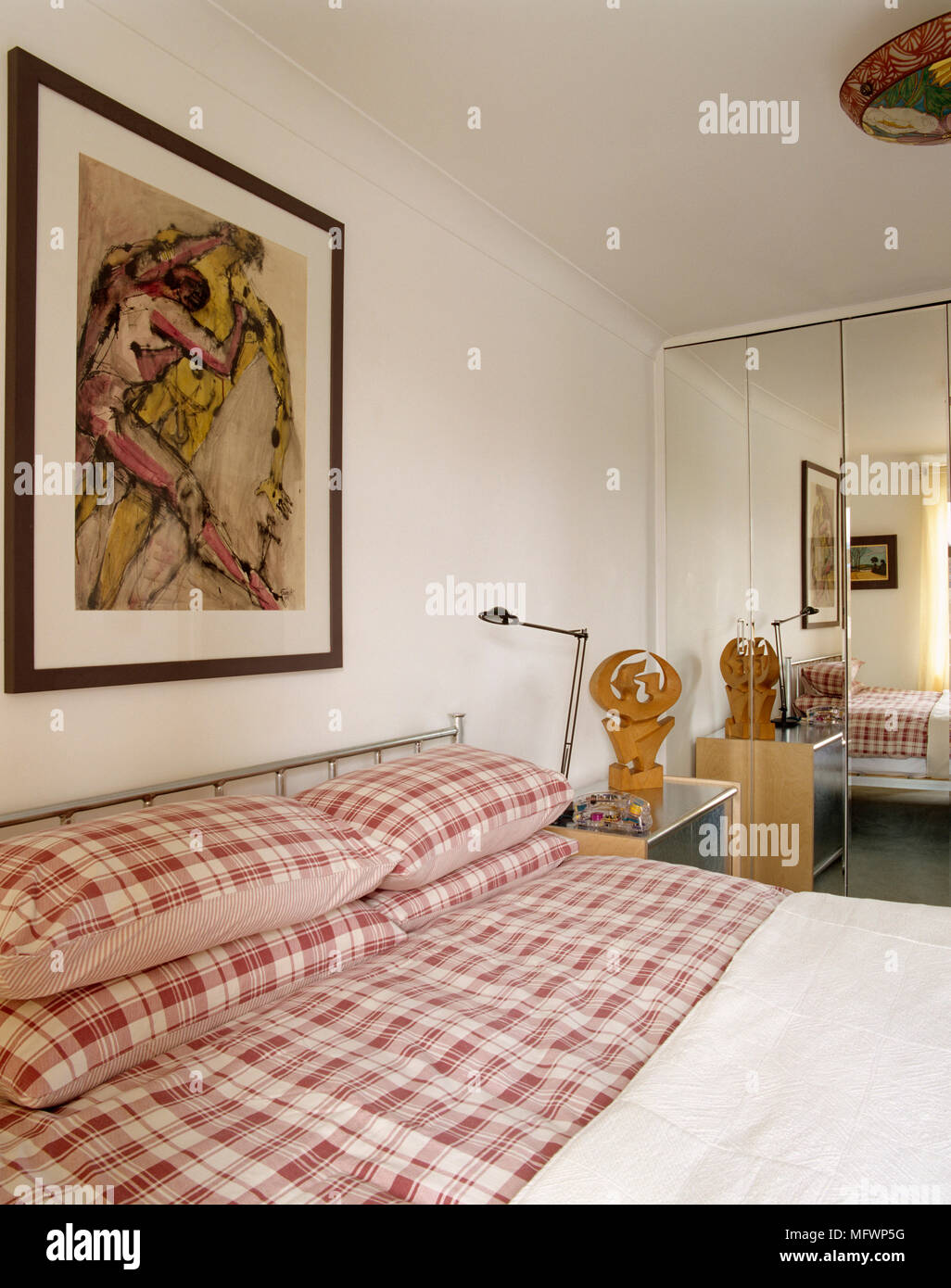 Metal bed with check pattern bed linen next to bedside cabinet Stock ...