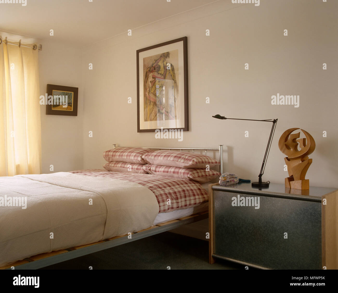 Metal bed with check pattern bed linen next to bedside cabinet Stock ...